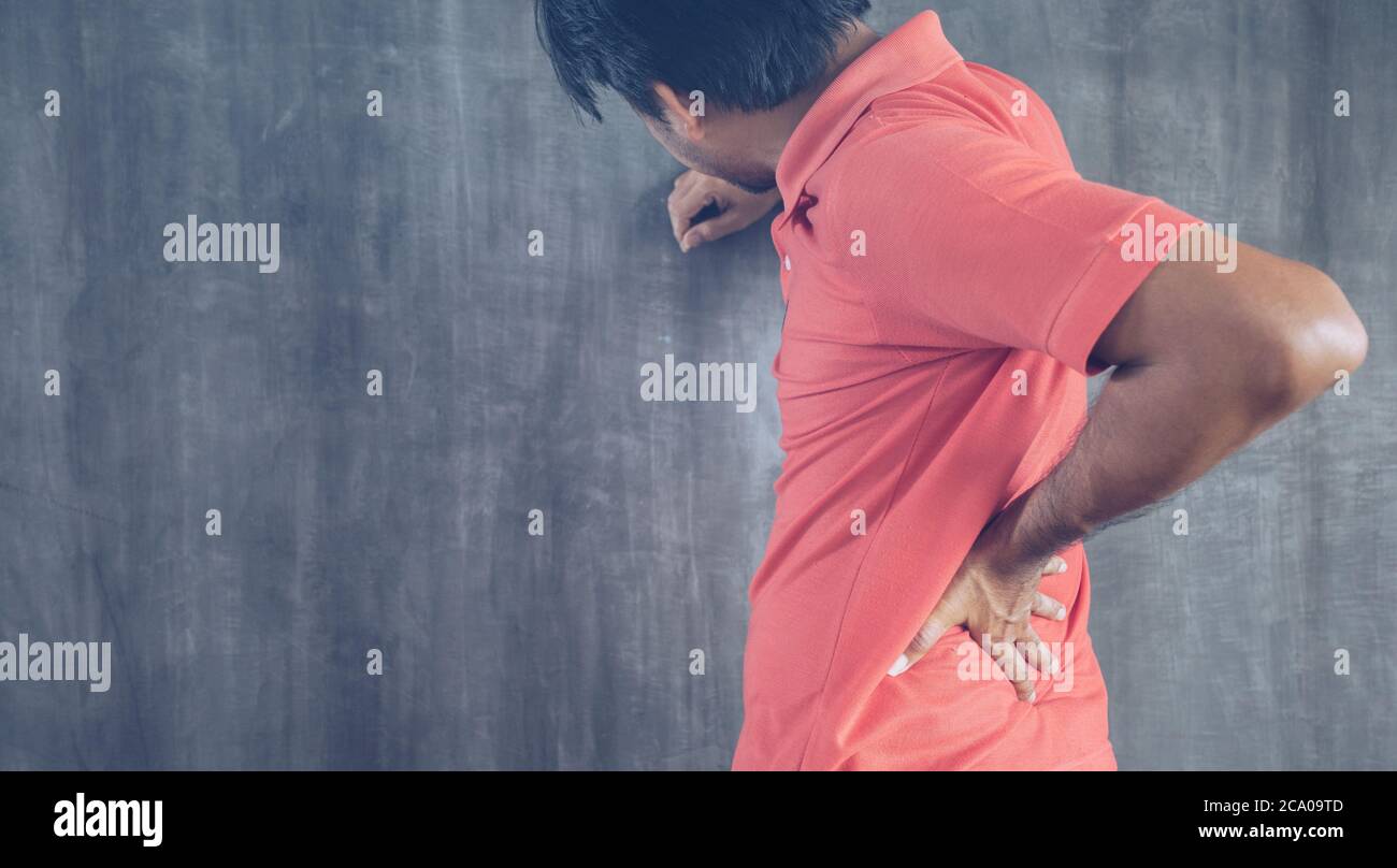 Hand of man touching her back pain on Cement wall background with copy ...