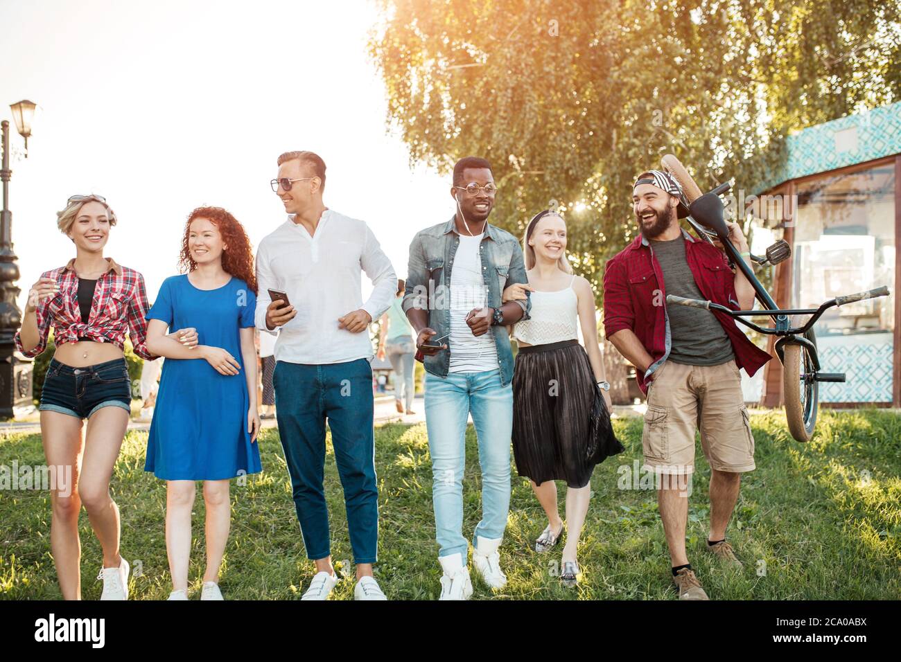 Happy adult guys and girls in casual wear enjoying a long walk ...