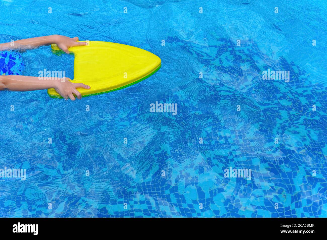 kid learning swimming with a floating pad on a swimming pool Stock ...