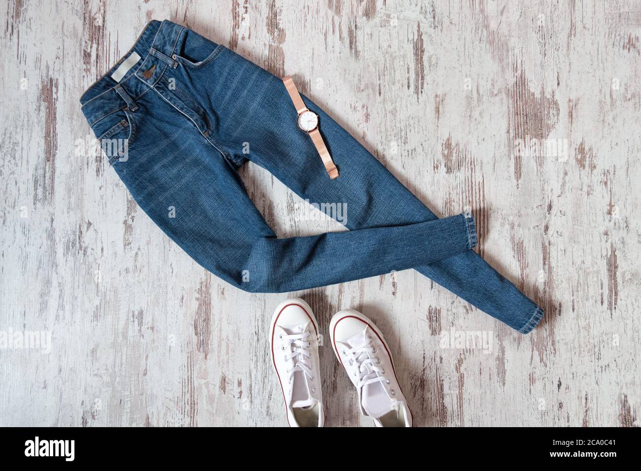 Blue jeans, watch and white sneakers on wooden background. Fashionable ...