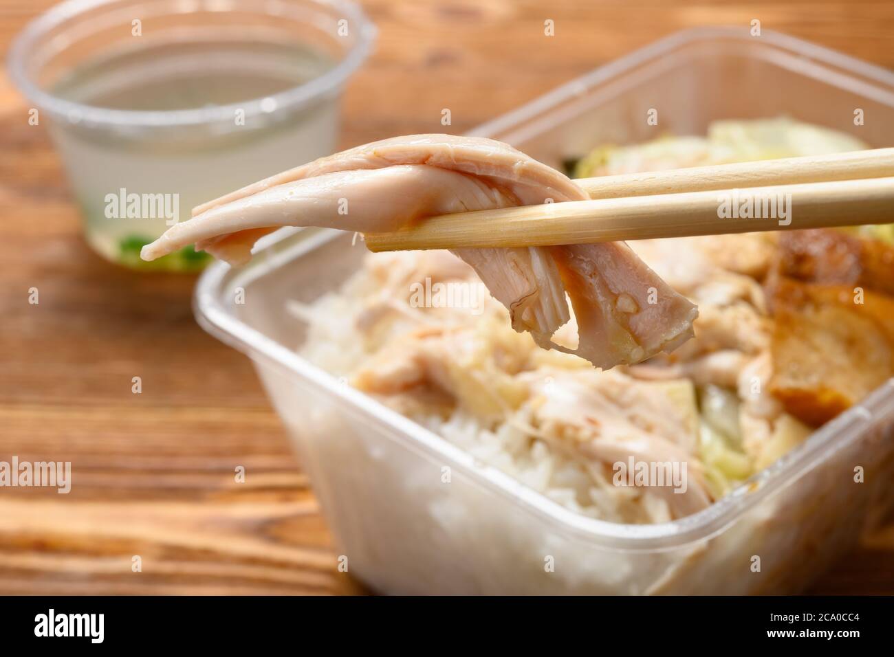 chopsticks picking up piece of boiled chicken from pack of fast food ...