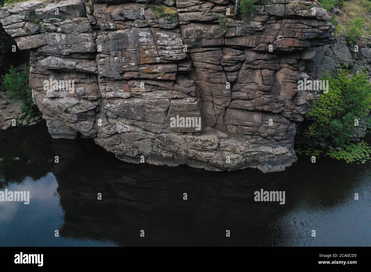 sheer cliff with large rocks above the water Stock Photo - Alamy