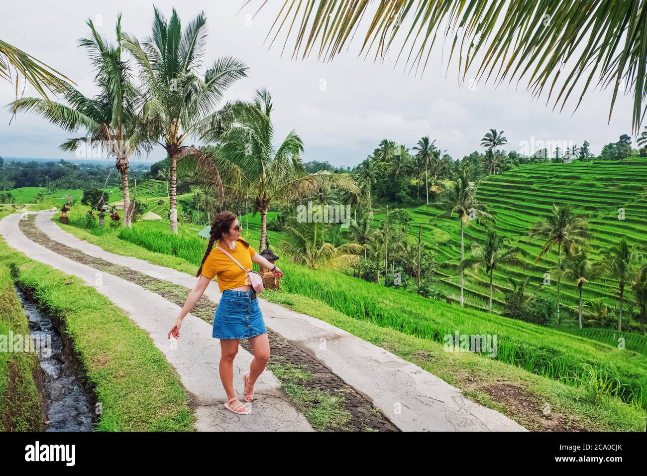 Young woman in yellow t-shirt walking through the rice fields in Bali ...