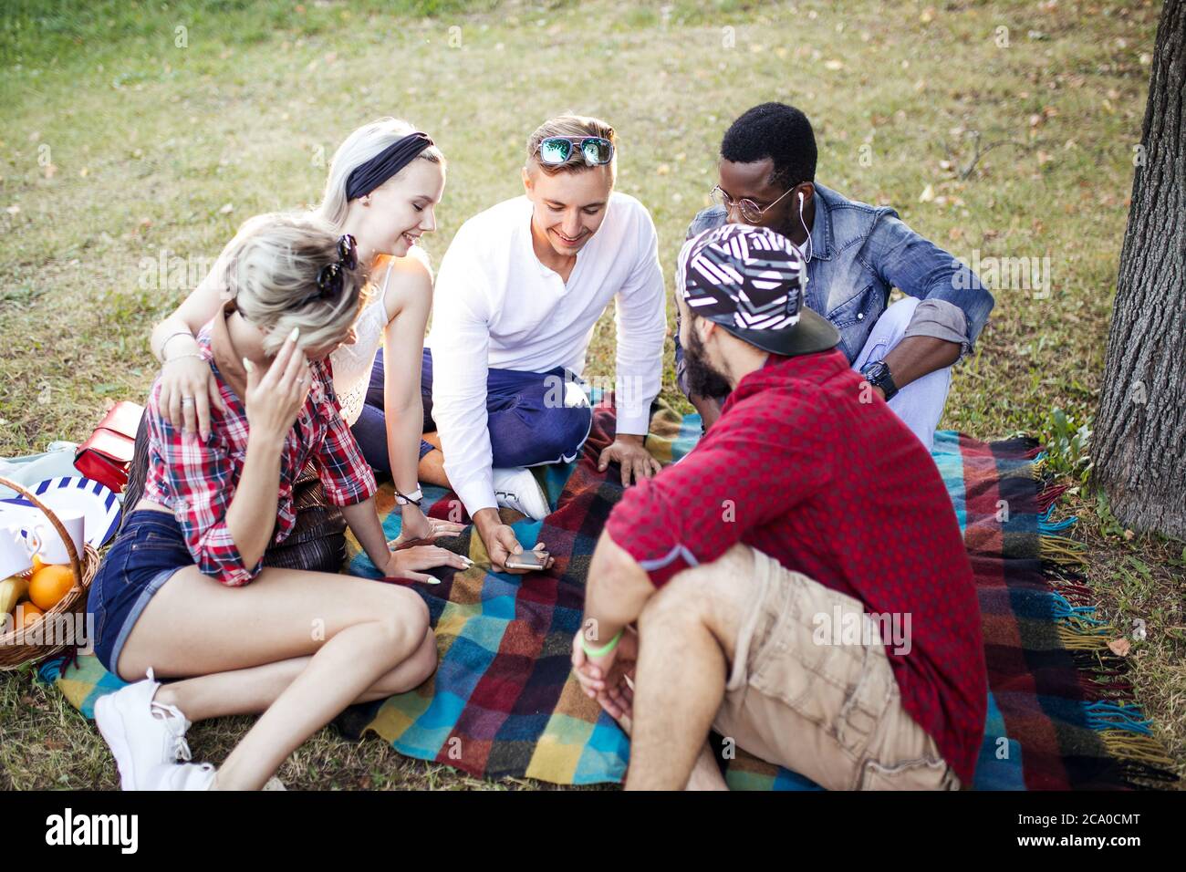Group of multiracial friends having fun while watching photos at ...