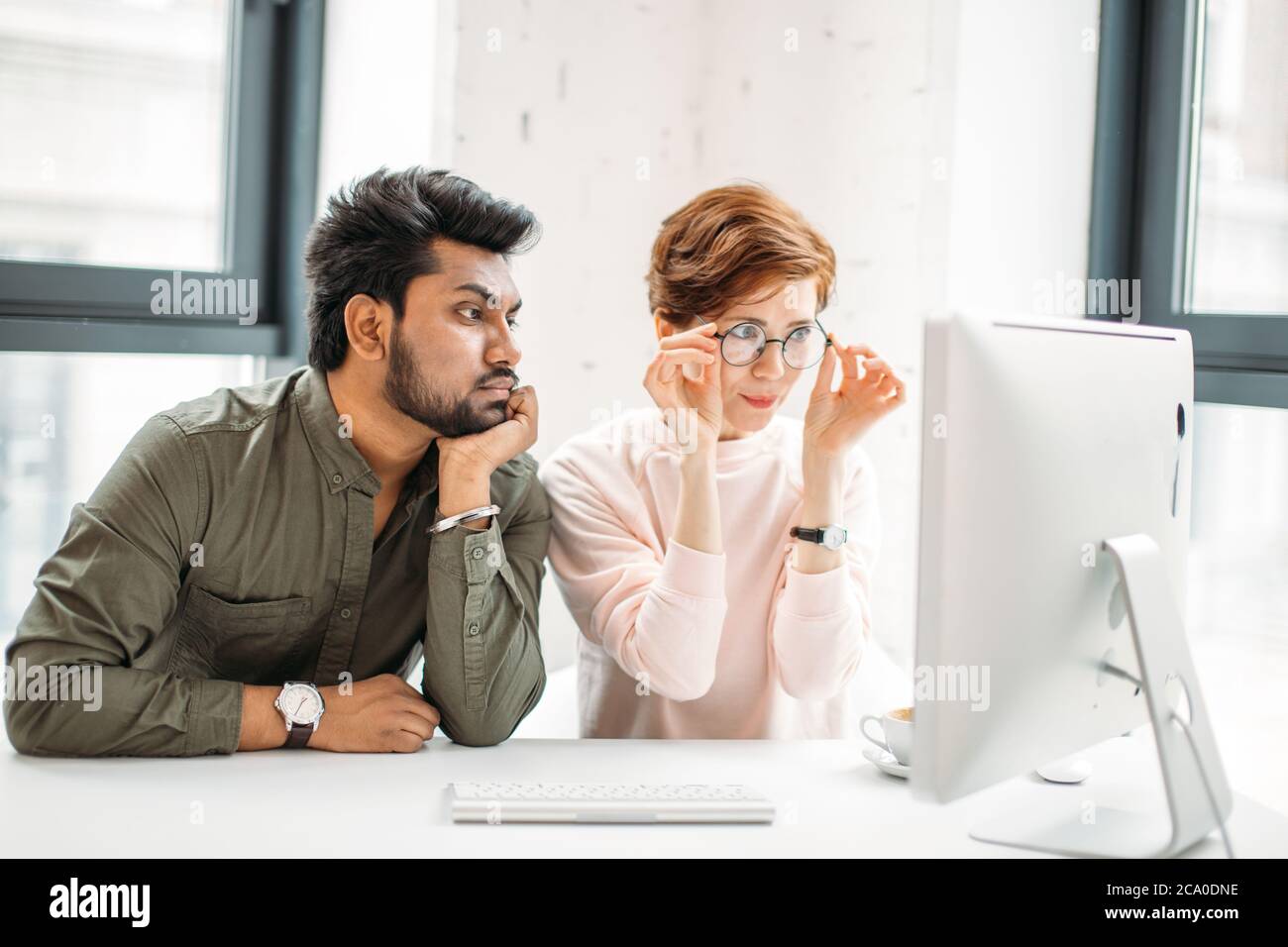 worried business man and woman colleagues looking at computer trying to ...