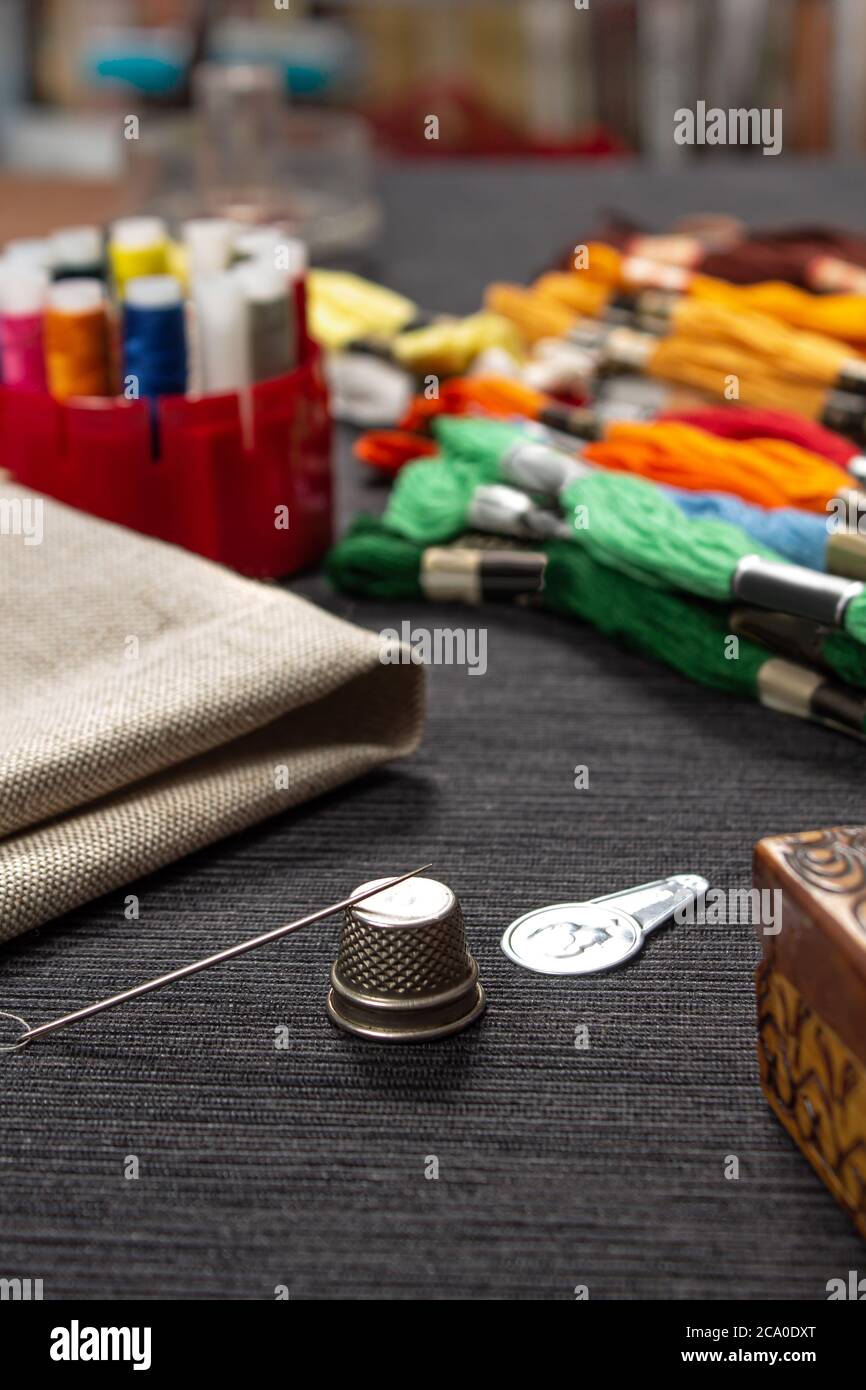 In the foreground a needle lying on a thimble. In the background ...