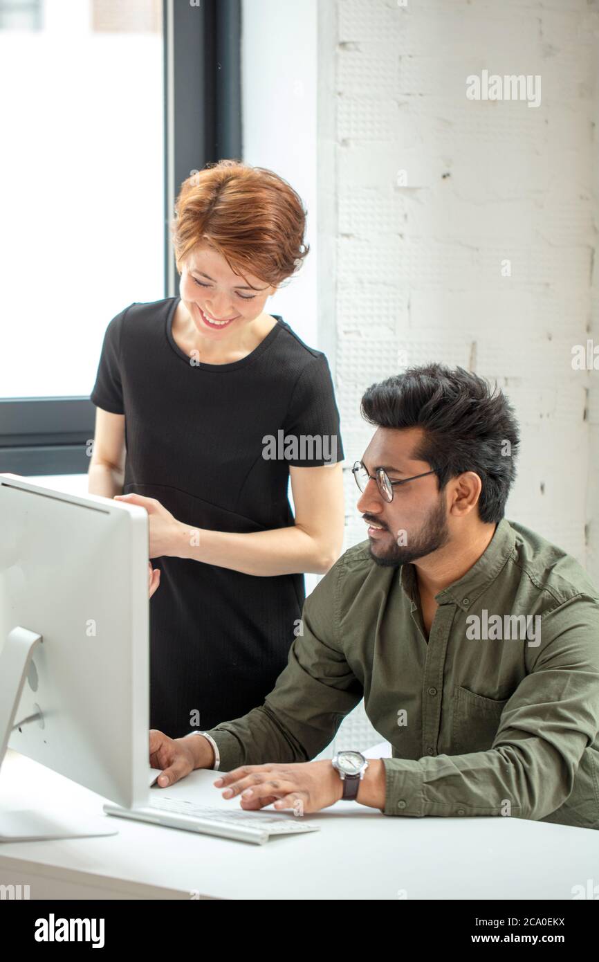 beautiful woman looking at monitor with smile and discussing with ...