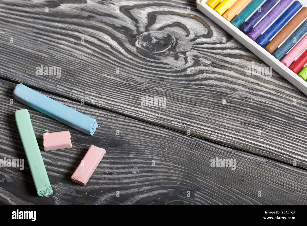 Chalk of different colors and pastels for drawing. On black pine planks ...