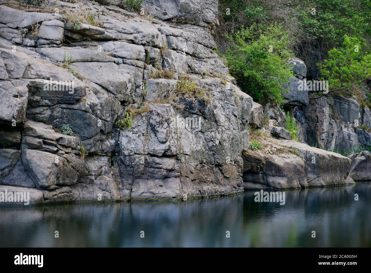 sheer cliff with large rocks above the water Stock Photo - Alamy