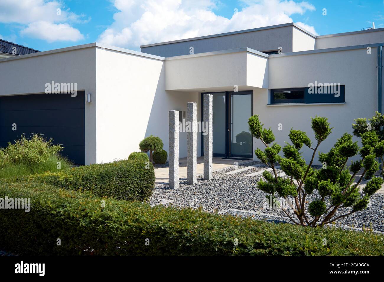 Front garden of a modern minimalist house with stone pillars, a hedge ...