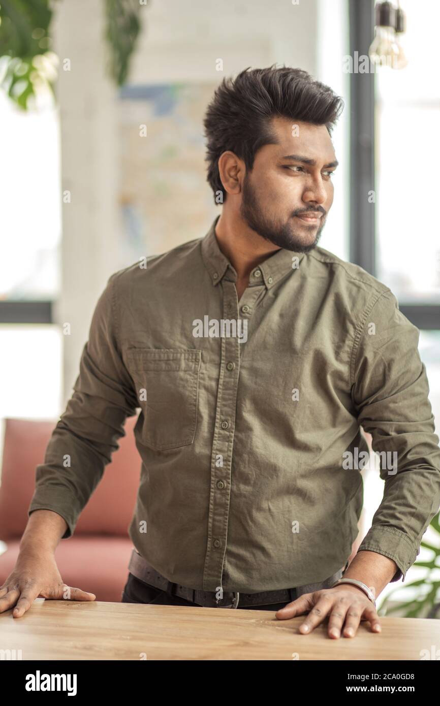 Young Indian man smiling at camera in his office Stock Photo - Alamy