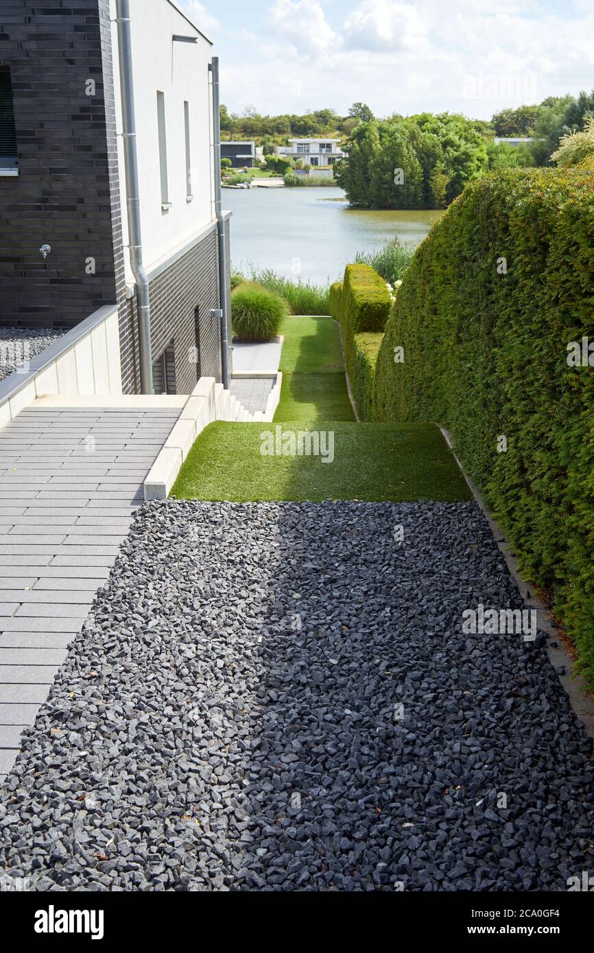 Ramp of grey gravel and green grass leading from the road to a body of ...