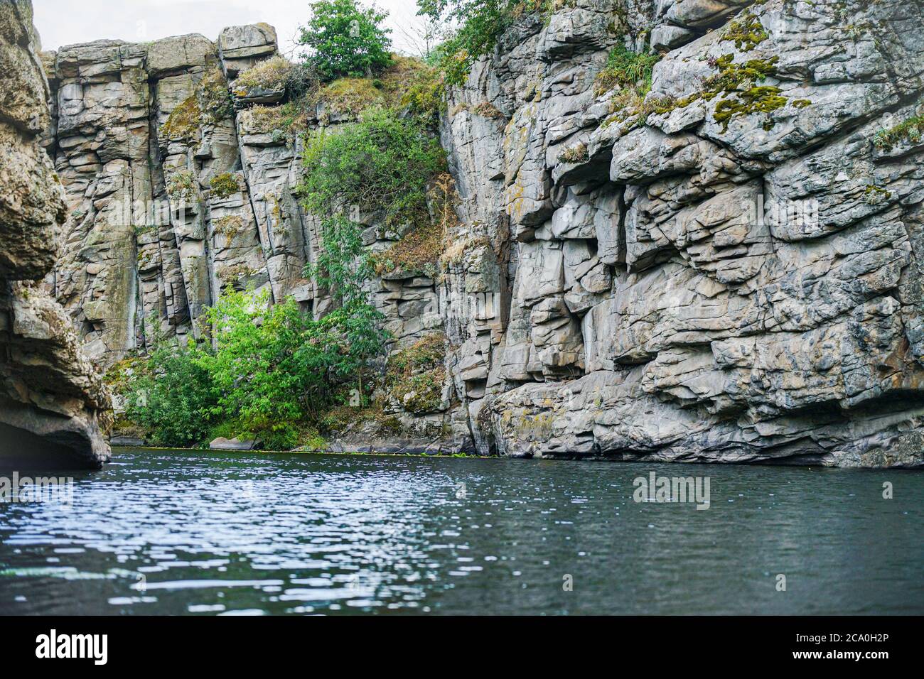 sheer cliff with large rocks above the water Stock Photo - Alamy
