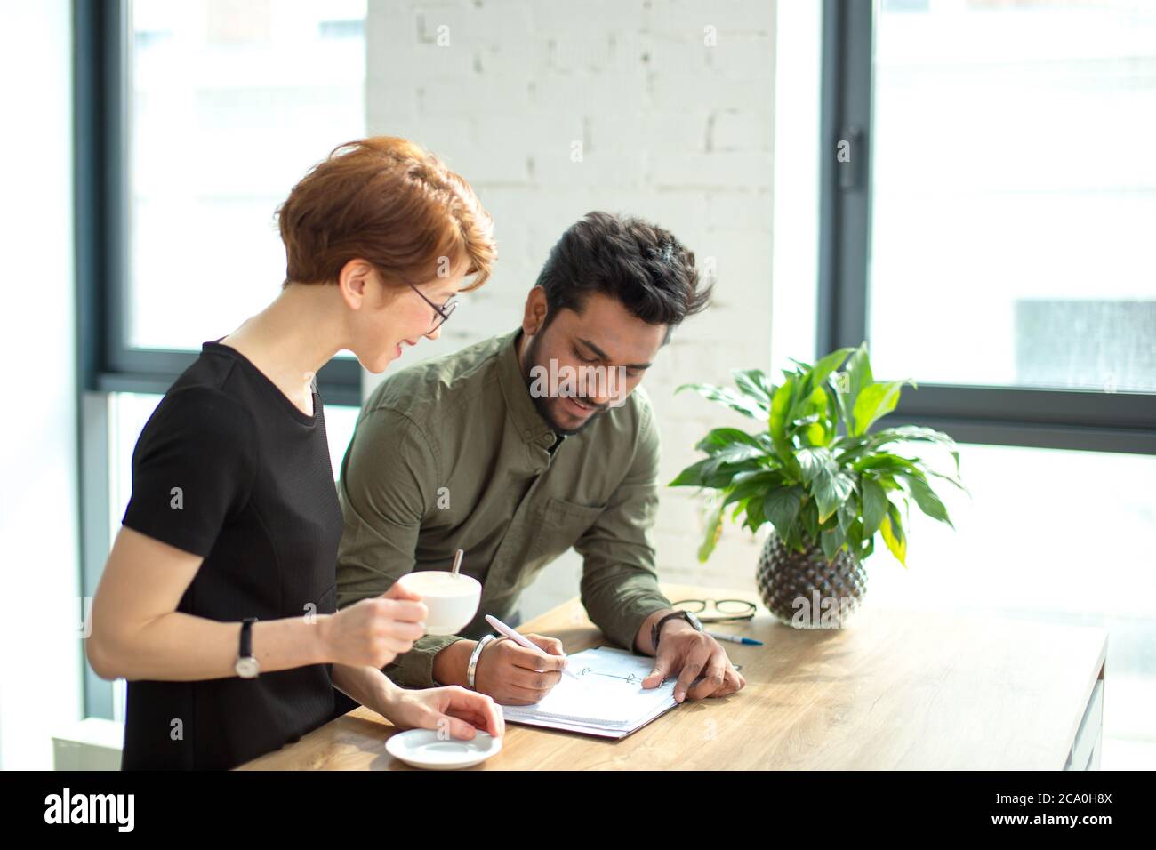 Two business people discuss meeting at table with documents and write ...