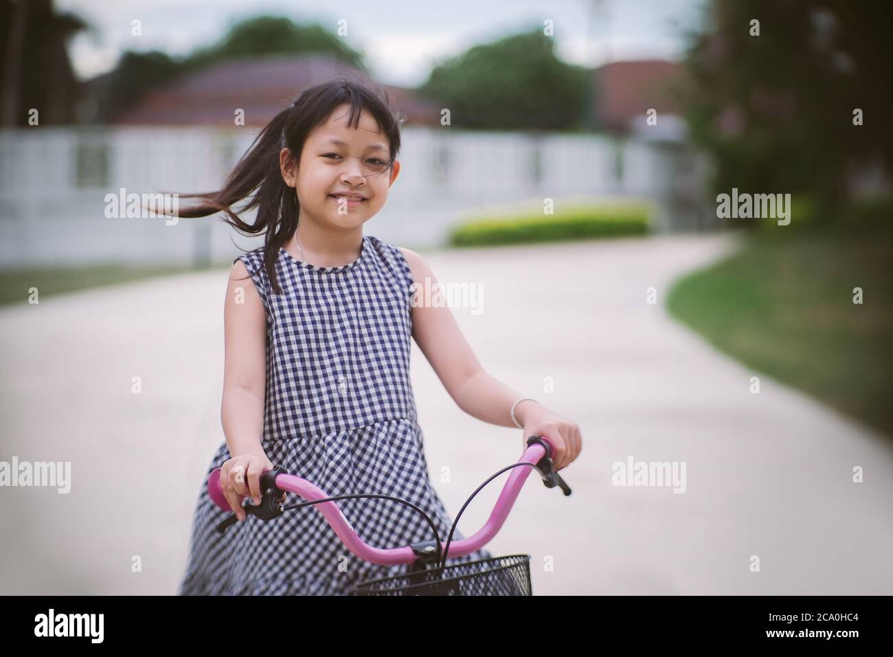 Asian little girl riding her bicycle outside with smile and happy ...