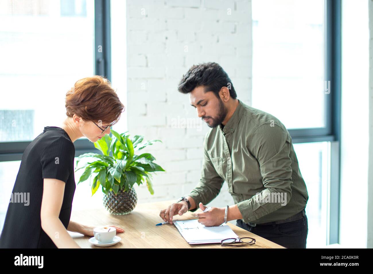 Two business people discuss meeting at table with documents and write ...