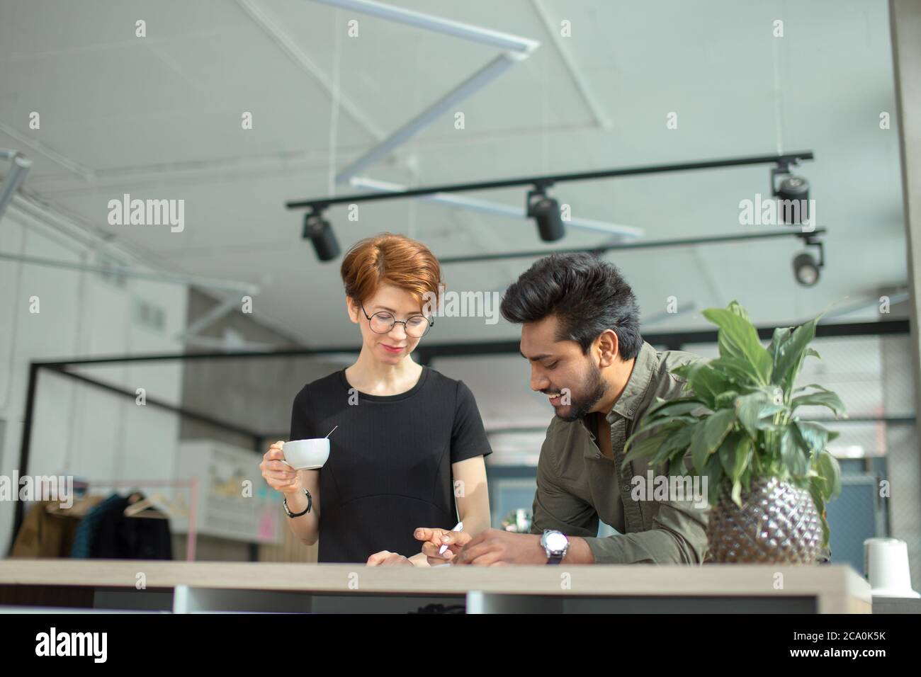 Two business people discuss meeting at table with documents and write ...