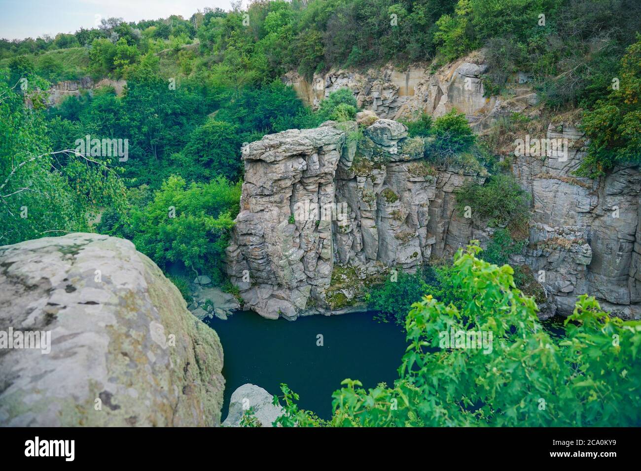sheer cliff with large rocks above the water Stock Photo - Alamy
