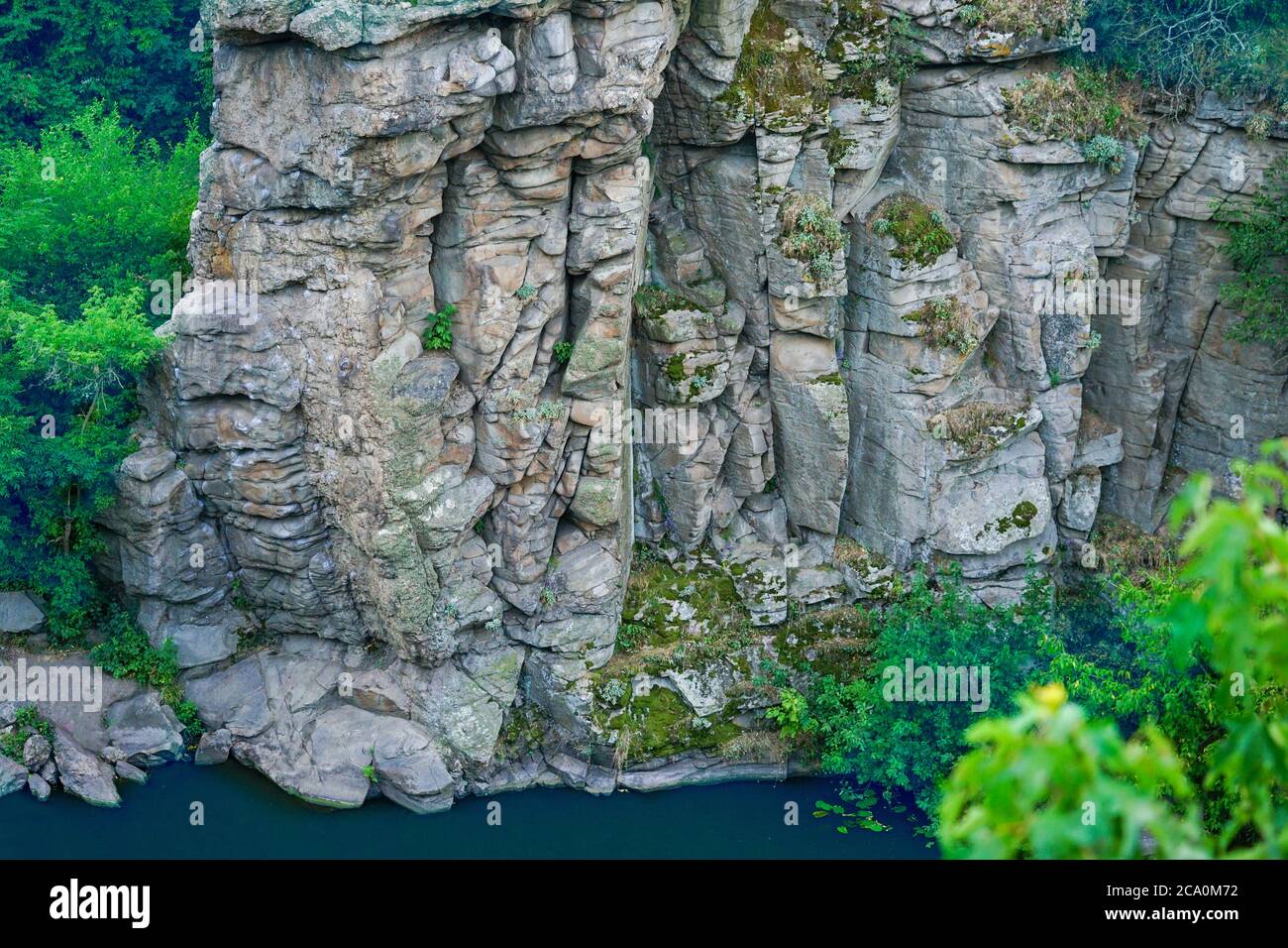 sheer cliff with large rocks above the water Stock Photo - Alamy