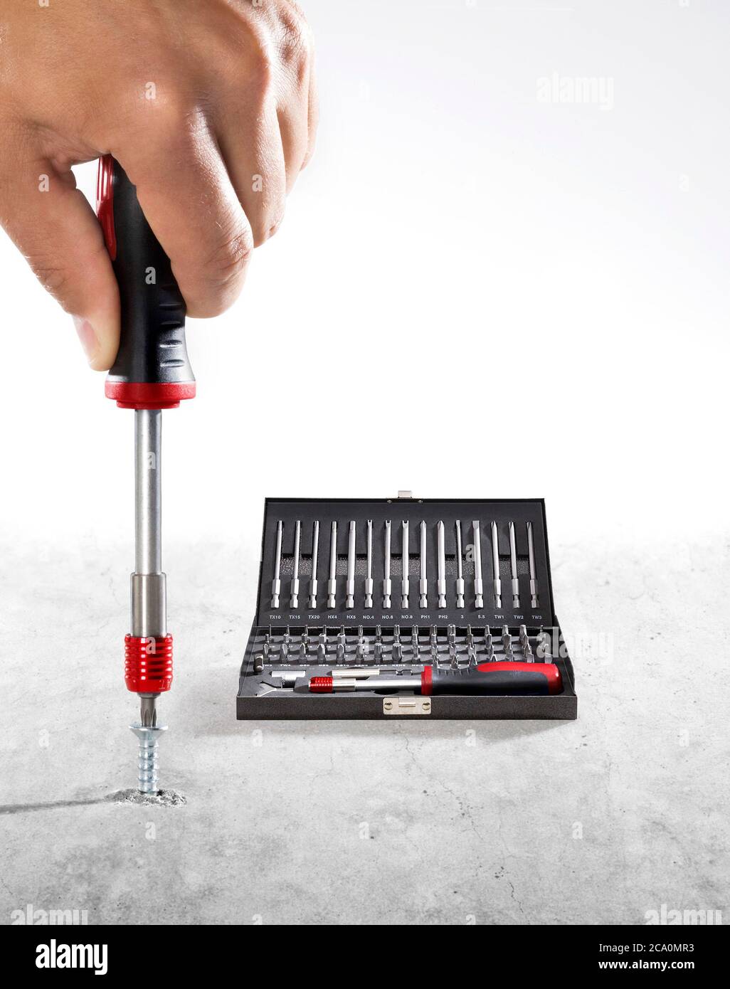 hand with screwdriver on grey stone background Stock Photo - Alamy