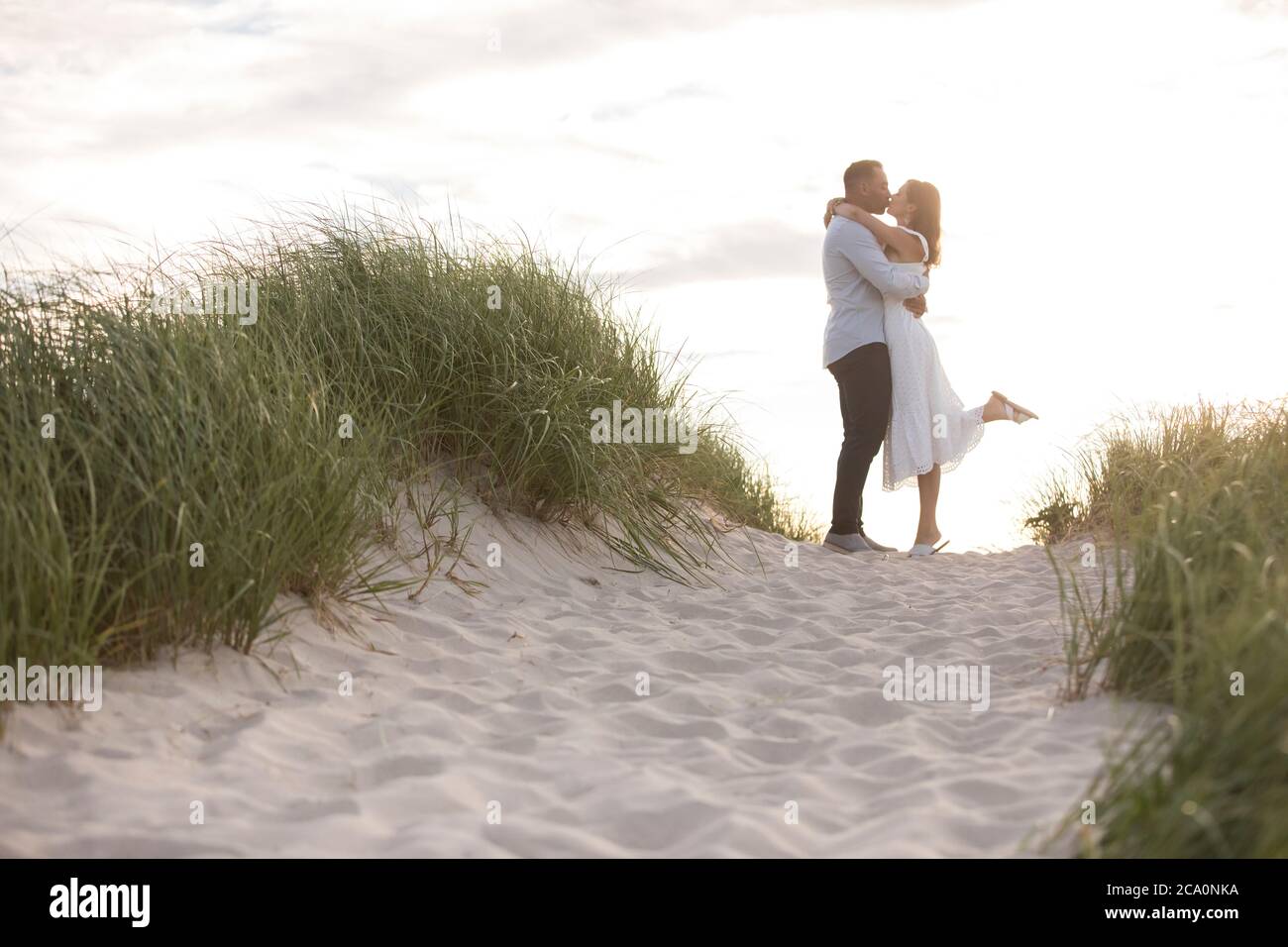 romantic couple kissing at beach from a distance Stock Photo - Alamy