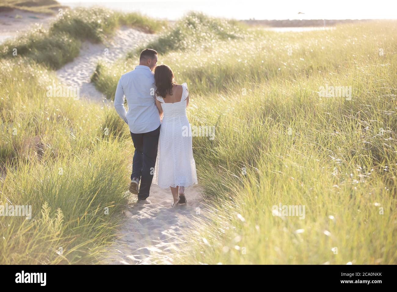 romantic couple from behind walking beach path arm in arm Stock Photo ...
