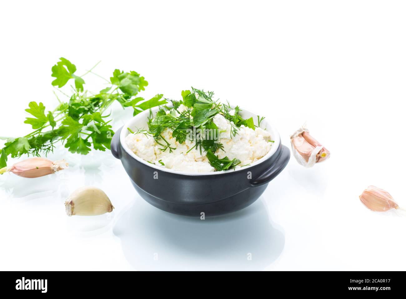 salted homemade cottage cheese with garlic and herbs in a bowl isolated ...