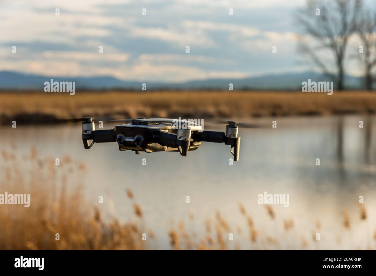 Small modern drone taking picture of lake at sunset Stock Photo - Alamy