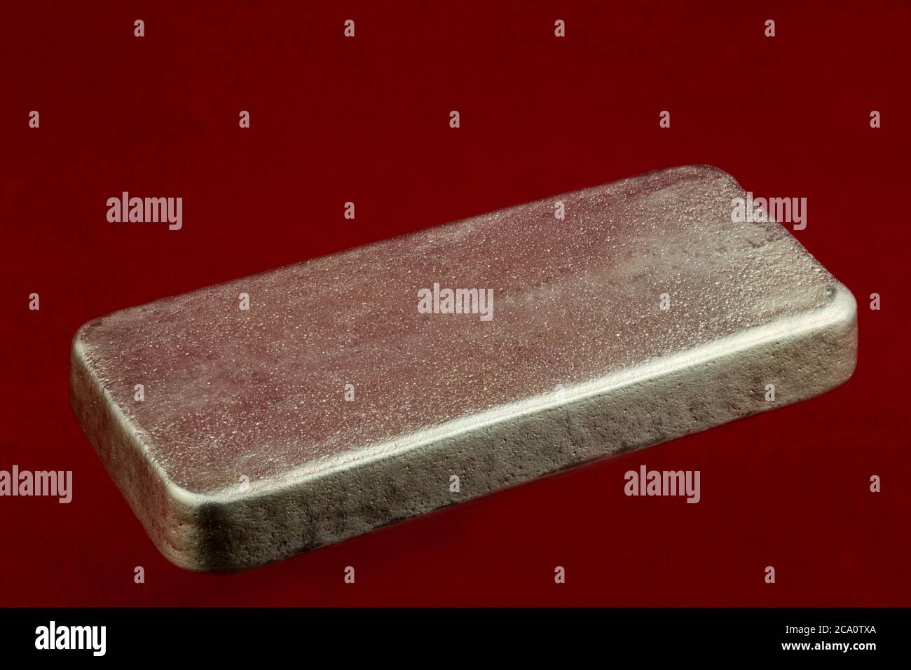 Solid silver ingot isolated on a red background Stock Photo - Alamy