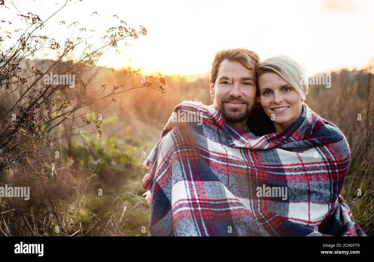 Young couple in love on a walk in autumn nature, looking at camera ...