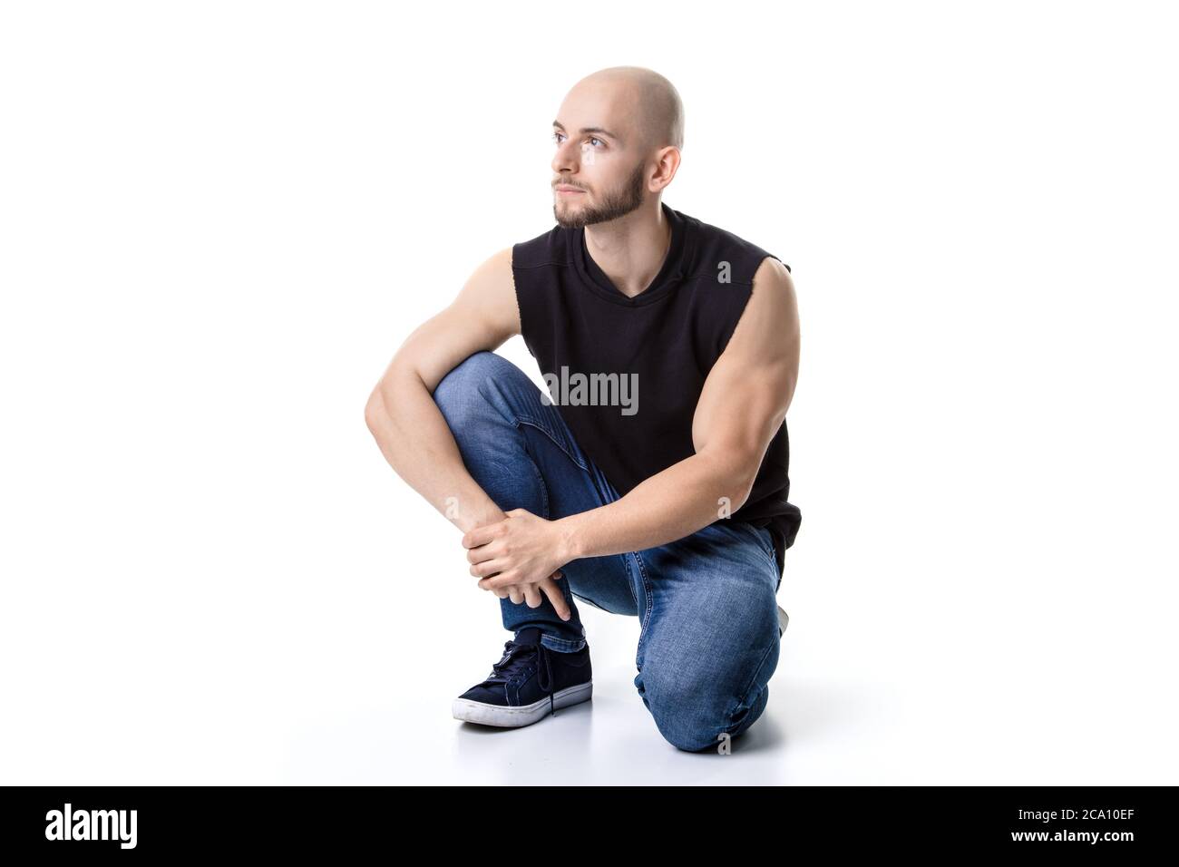 muscular man with eye on something look to side while squat on floor ...