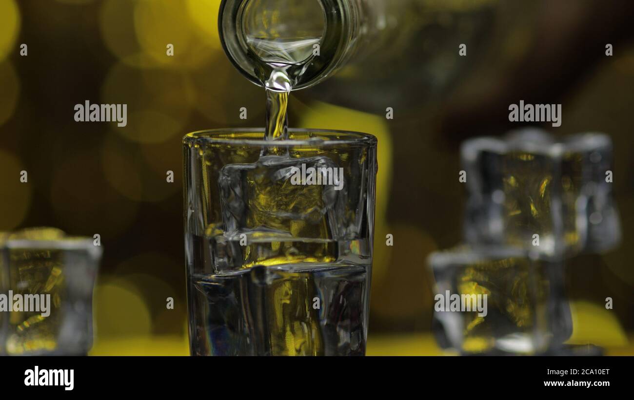 Bartender pouring up frozen vodka from bottle into shot glass against ...