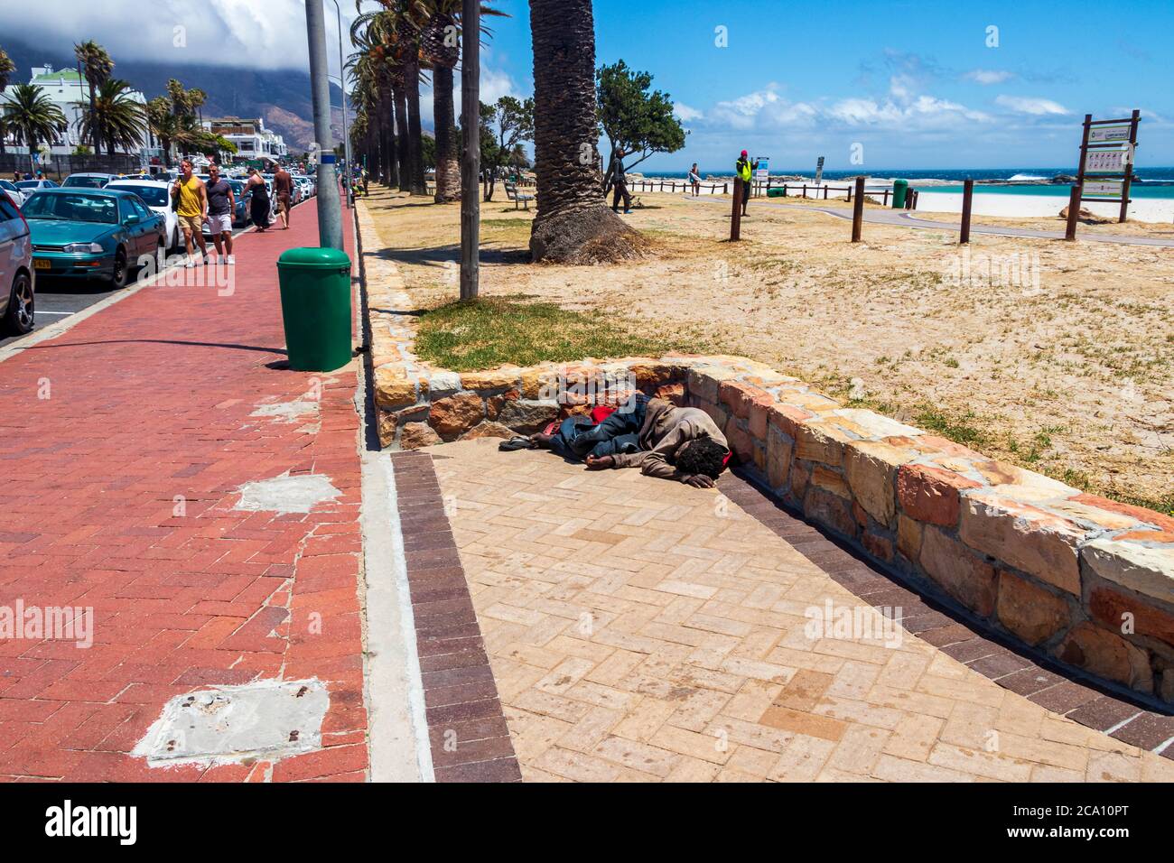 Poor homeless man sleeps on the street in the heat in Camps Bay, Cape ...
