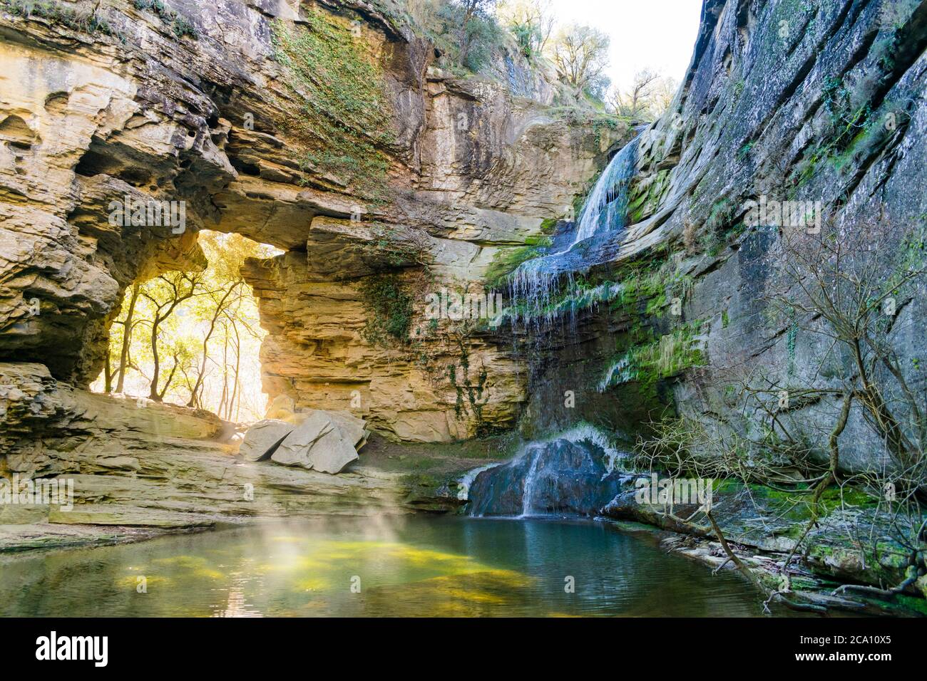 Magical place with a waterfall and an entrance of light in the middle ...