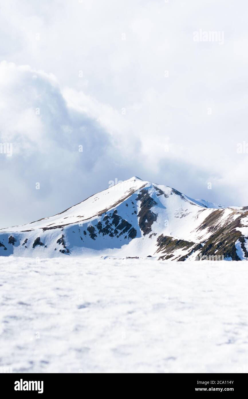 Impressive snowy peaks behind the snow covered hill Stock Photo - Alamy