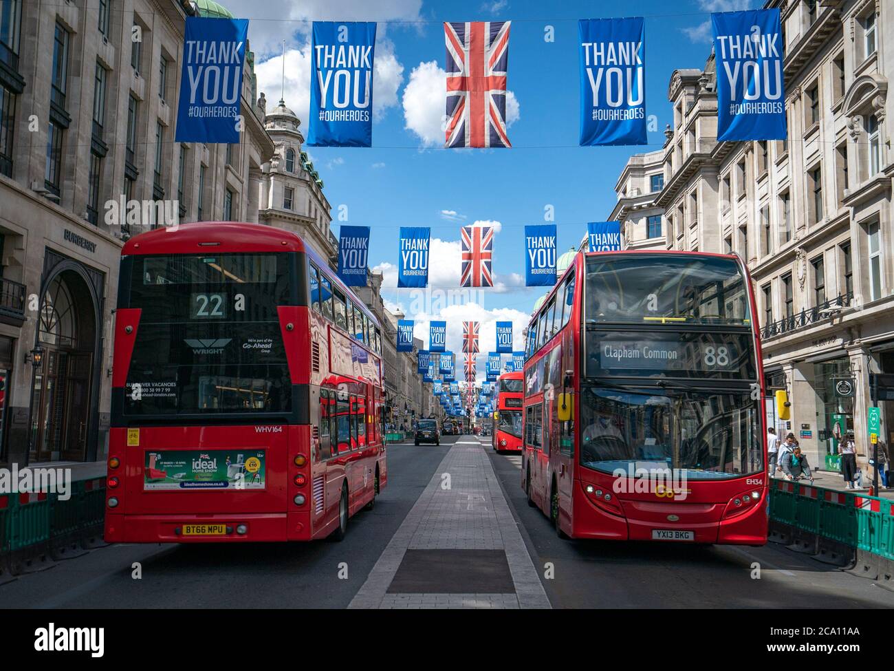 City of London, England on 3 August 2020. Red Buses pass below Thank ...
