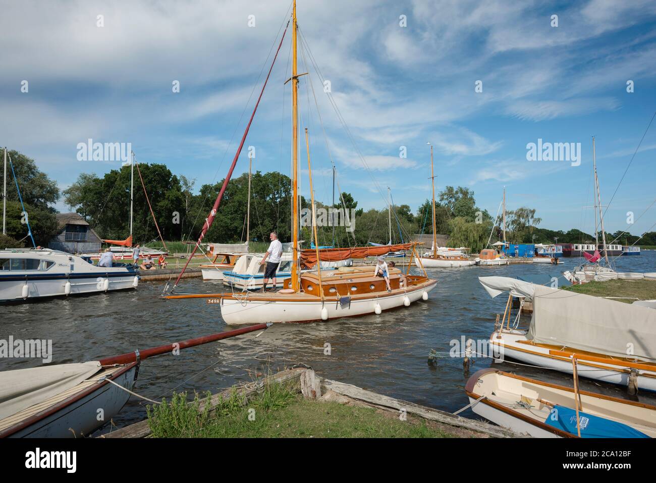 Norfolk Broads, view in summer of a pleasure boat being steered along ...