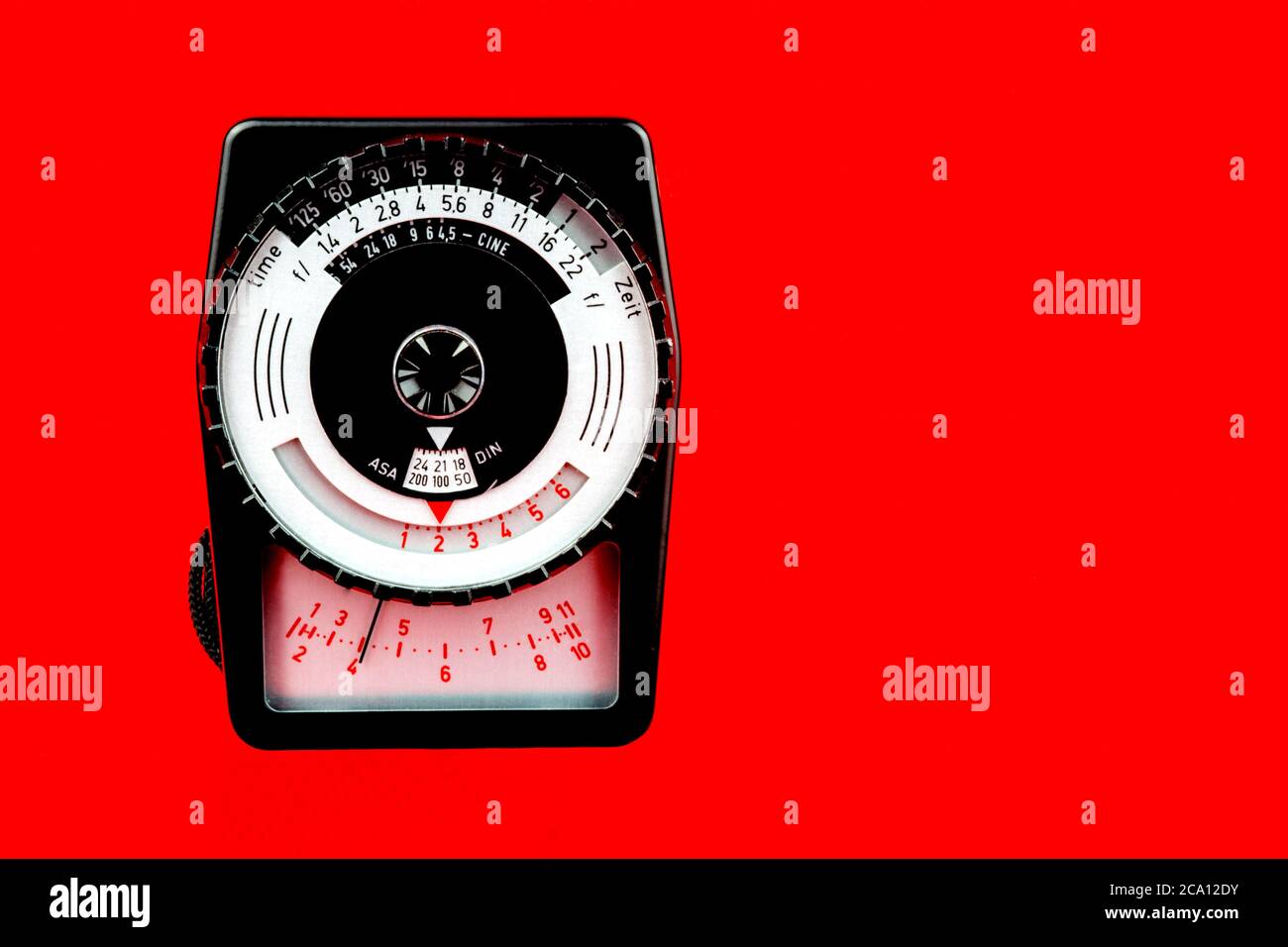 Vintage photographic exposure meter isolated against a red background ...