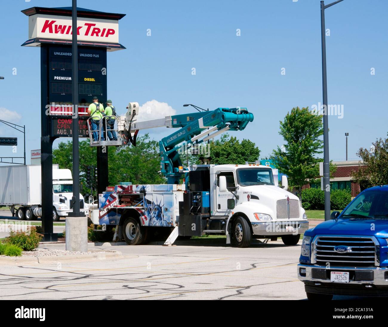 Two men installing sign, working from Kenworth truck with Altec boom ...