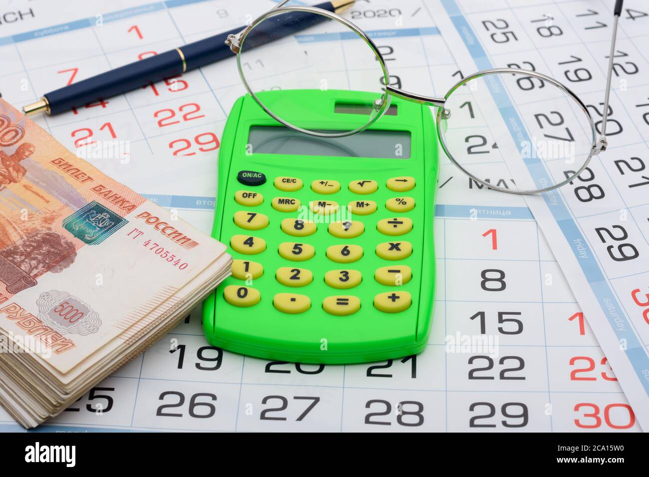 Calculator in the center of the frame, money on the sides, a pen and ...