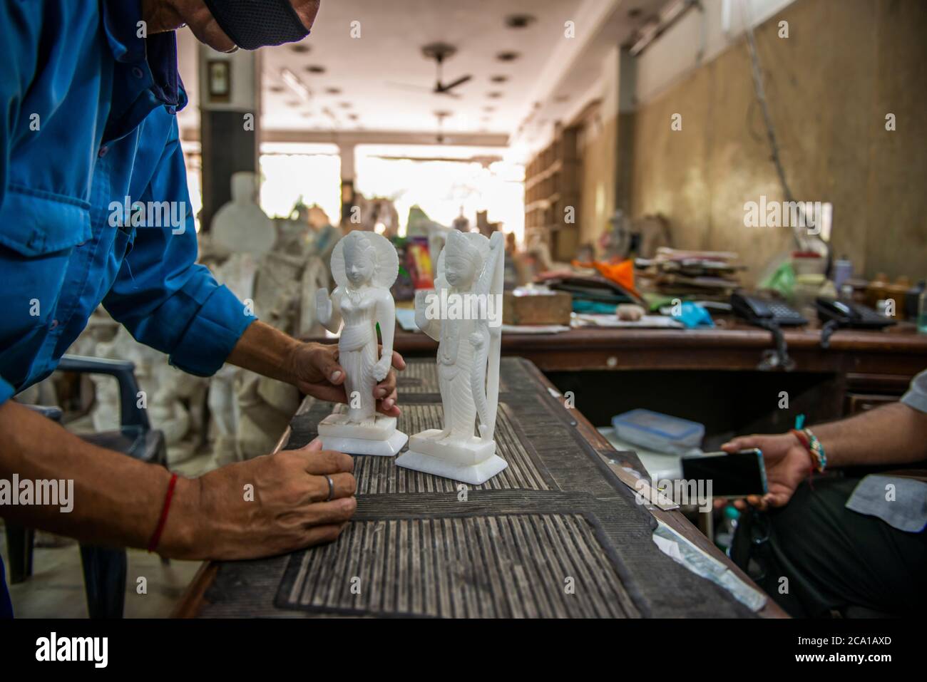 A worker holds unpainted stone statue at a shop.Lord Rama is one of the ...