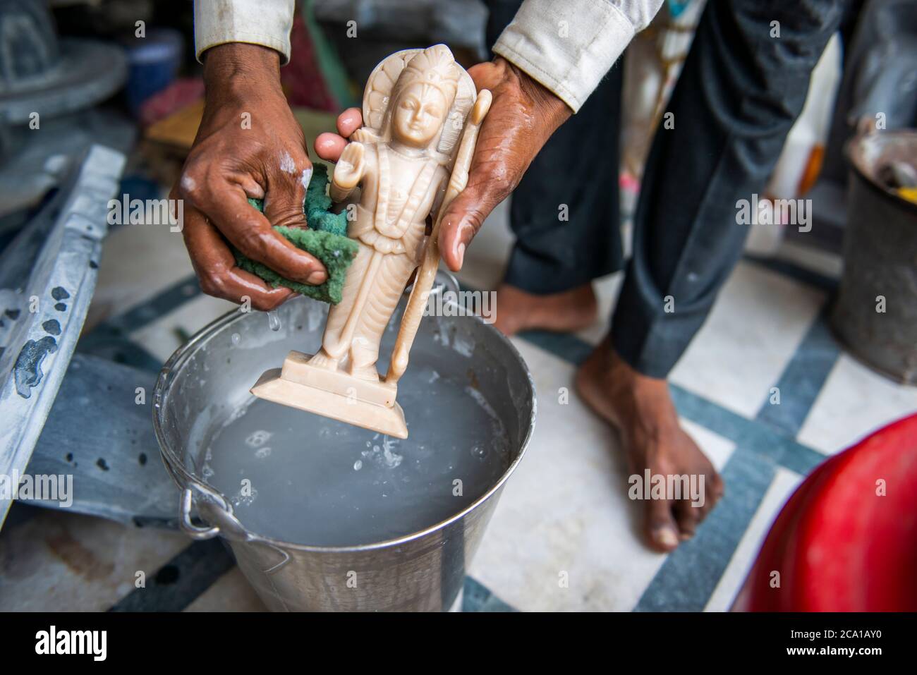 A man cleans the stone carved idol of lord Rama in a bucket with water ...