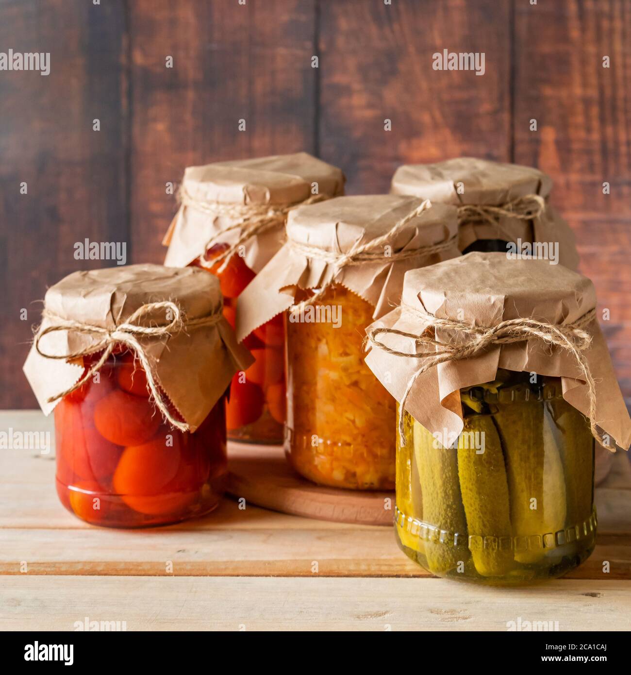 Pickled farm vegetables in glass jars on a wooden background. Fermented ...