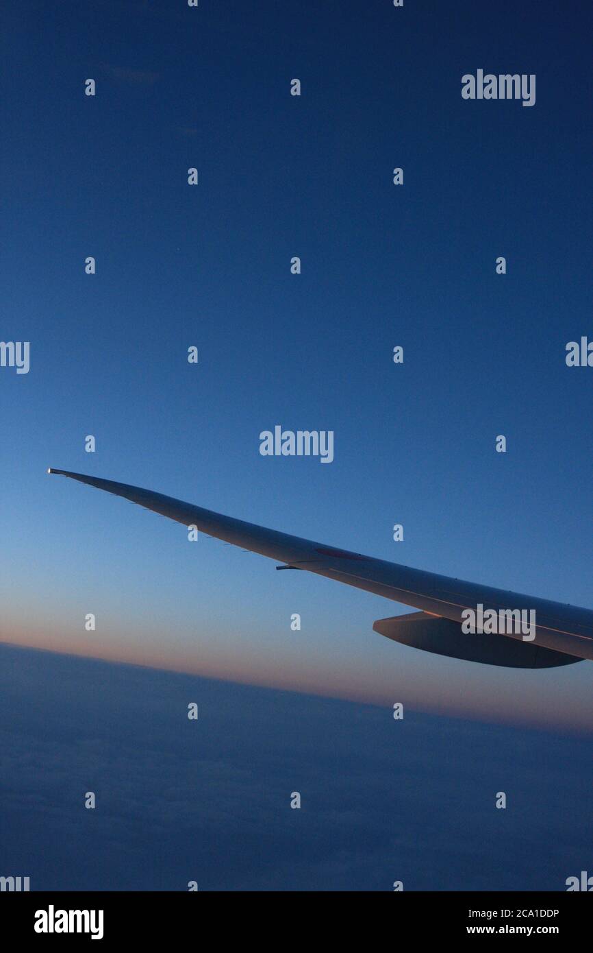 Airplane wing with dusk and deep blue sky on flight to Japan Stock ...