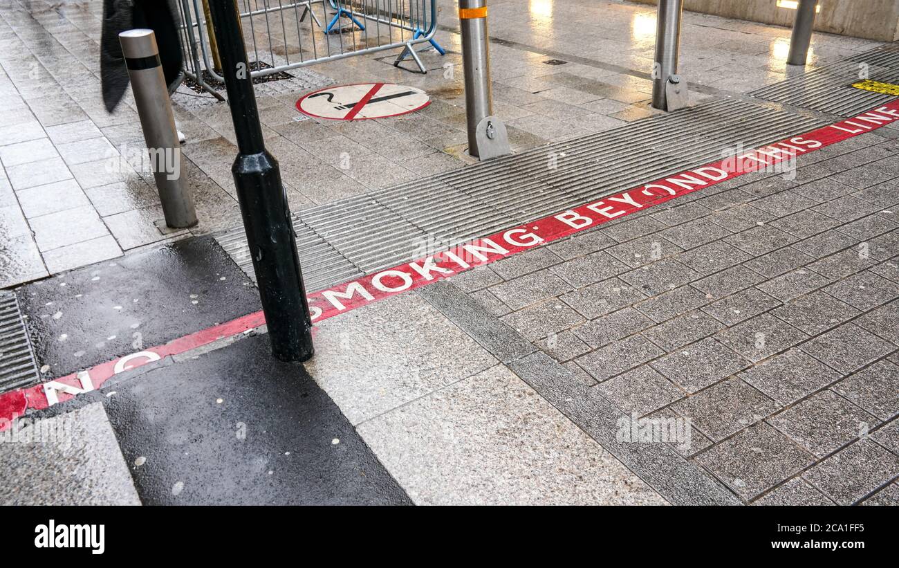 Red line on pavement with NO SMOKING text, sign near also informing ...
