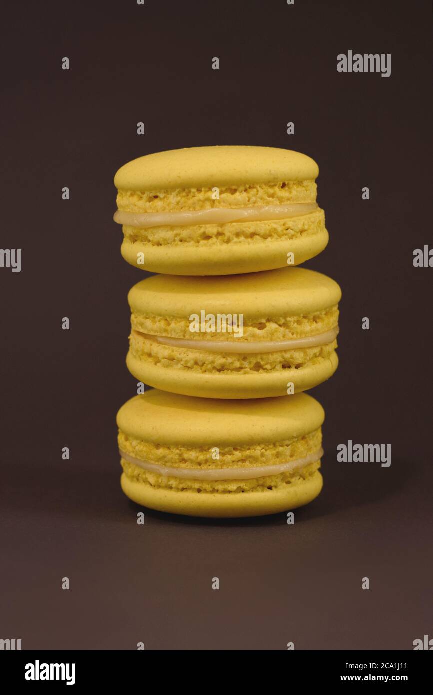 Three tasty french yellow colored macarons on the brown background ...