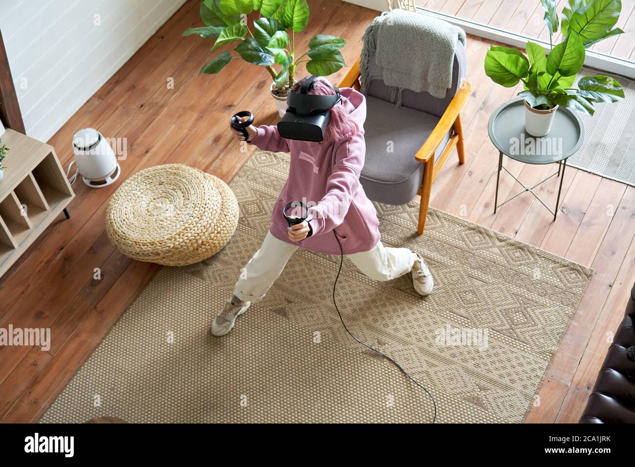 Teen girl pink hair wear vr goggles play virtual reality game at home ...