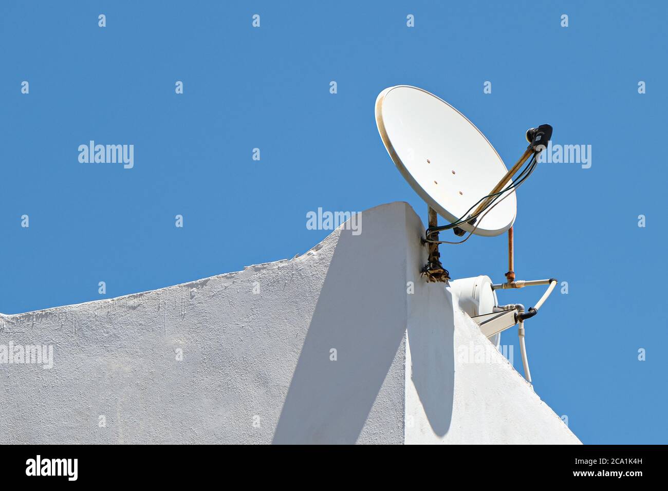 Satellite dish antenna mounted on a roof of white building Stock Photo ...