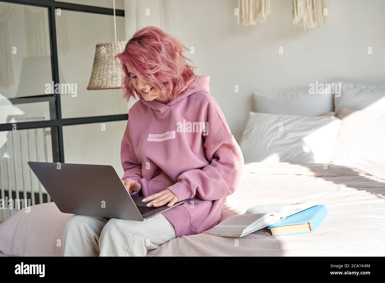 Smiling teen girl student with pink hair use laptop online learning sit ...