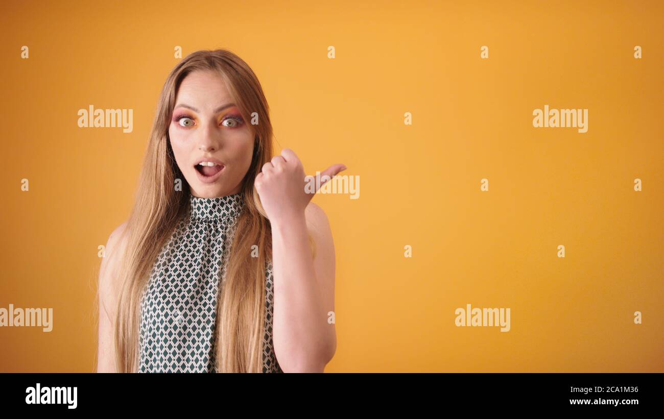 Fascinating long hair girl with amazed surprised face pointing to copy ...